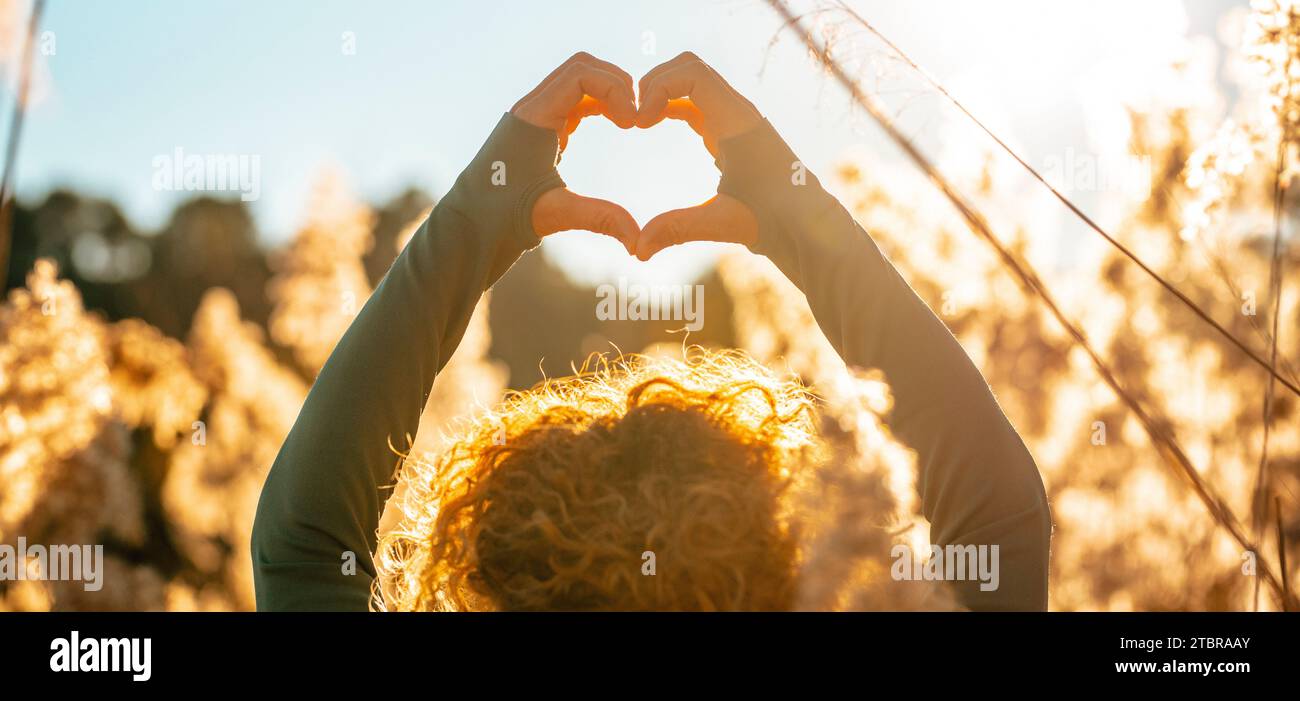 Back view of woman doing heart gesture with hands in front of an ...