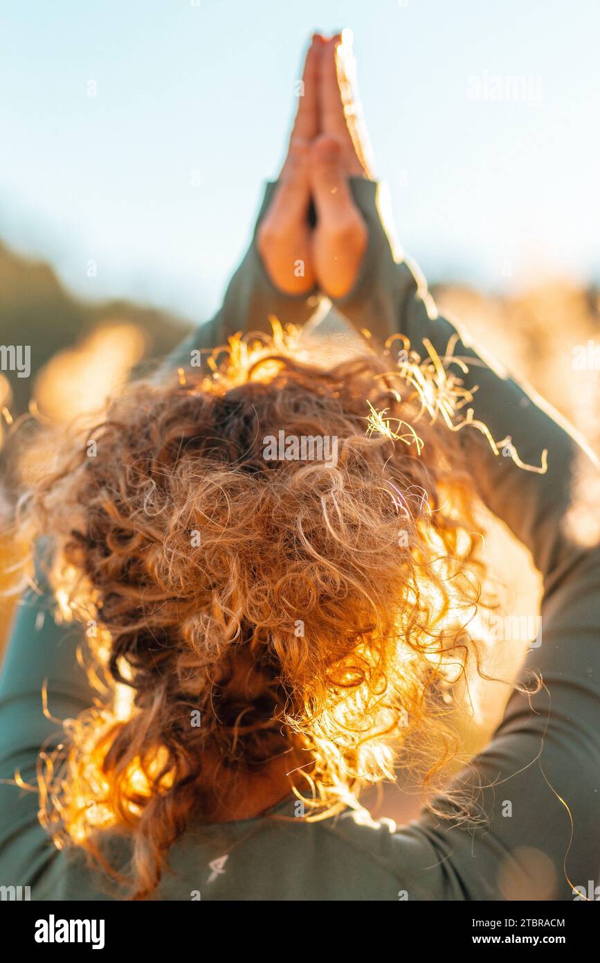 Close up of back lady with blonde curly hair and hands together to ...