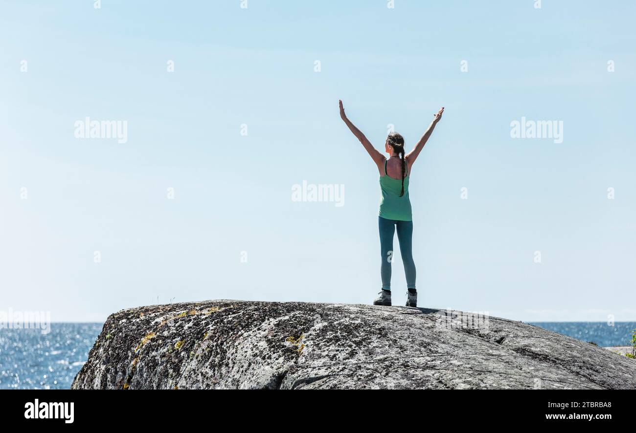 Woman with outstretched arms on rocky peak by the sea hi-res stock ...