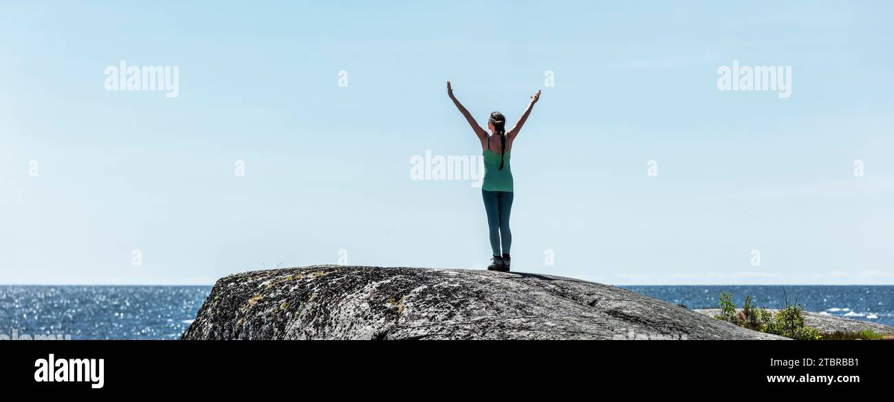 Woman with outstretched arms on rocky peak by the sea hi-res stock ...
