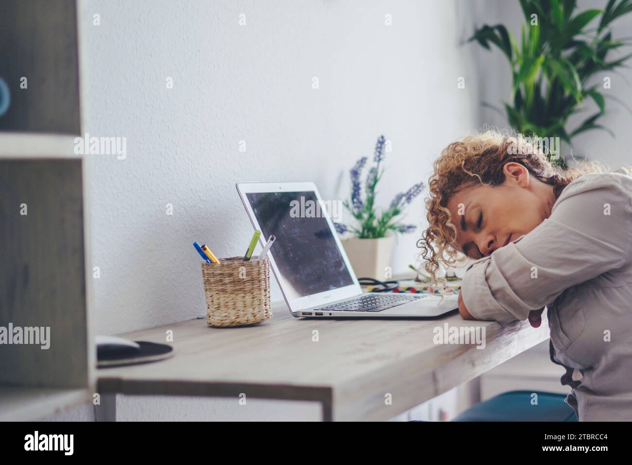 One woman asleep in front of an open laptop in home office workplace ...