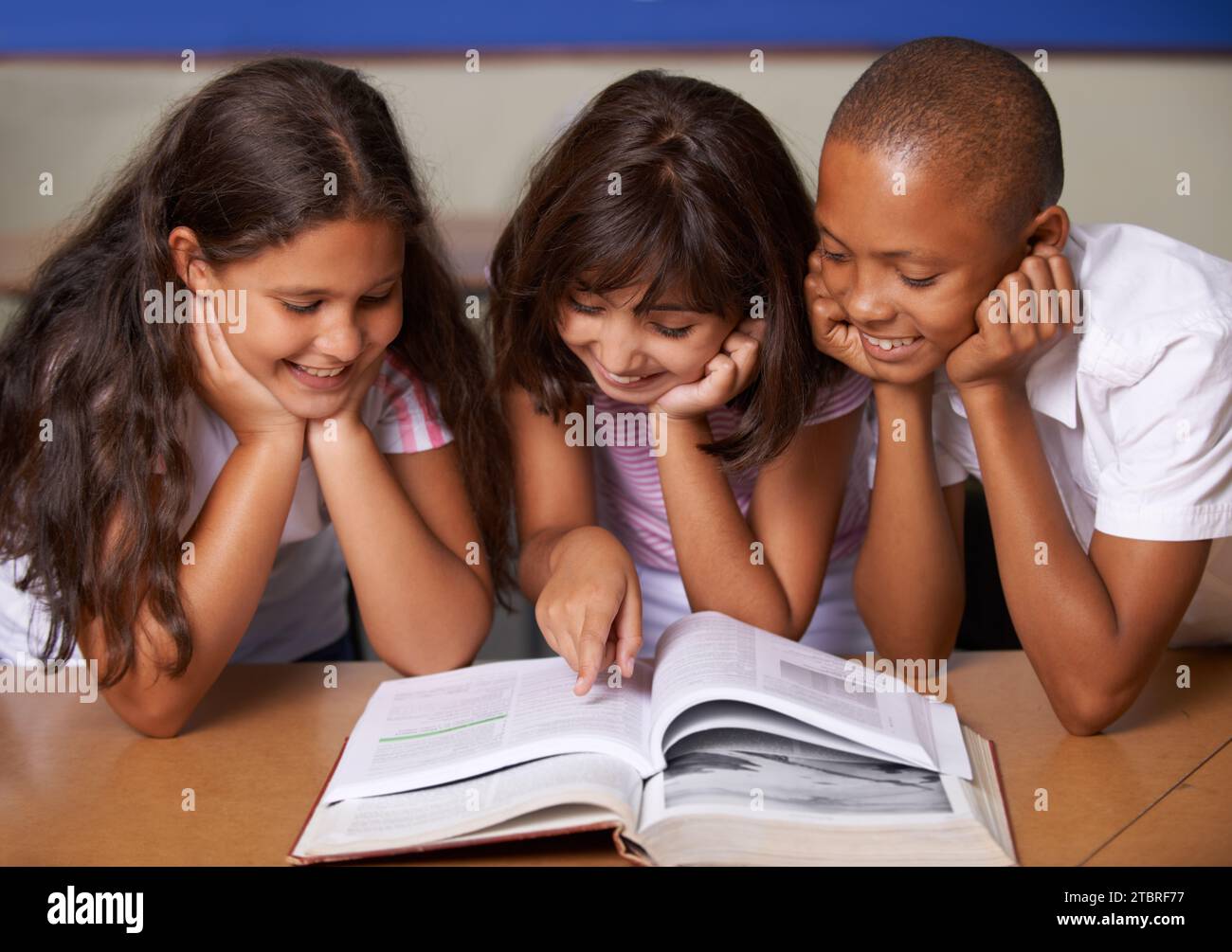 School kids, reading and happy in classroom with book, pointing and ...