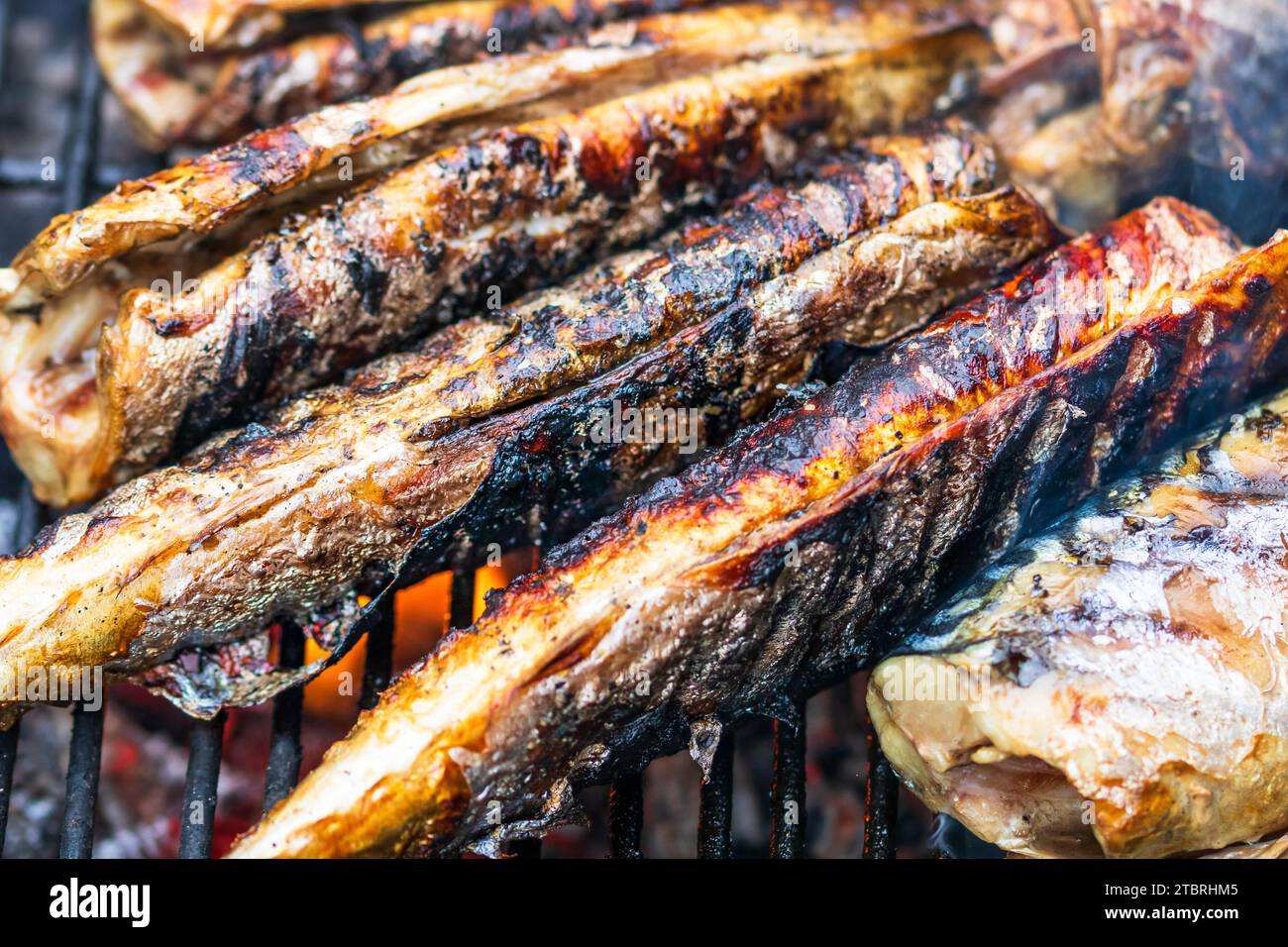 Grilled fish with smoke on a charcoal barbecue. Close up fish on the ...