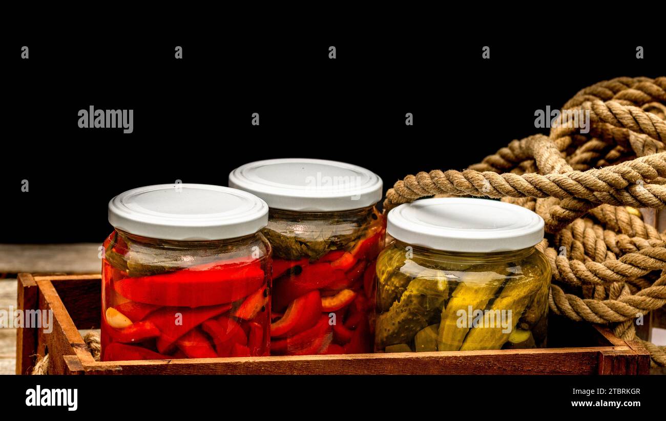 Wooden crate with glass jars with pickled red bell peppers and pickled ...