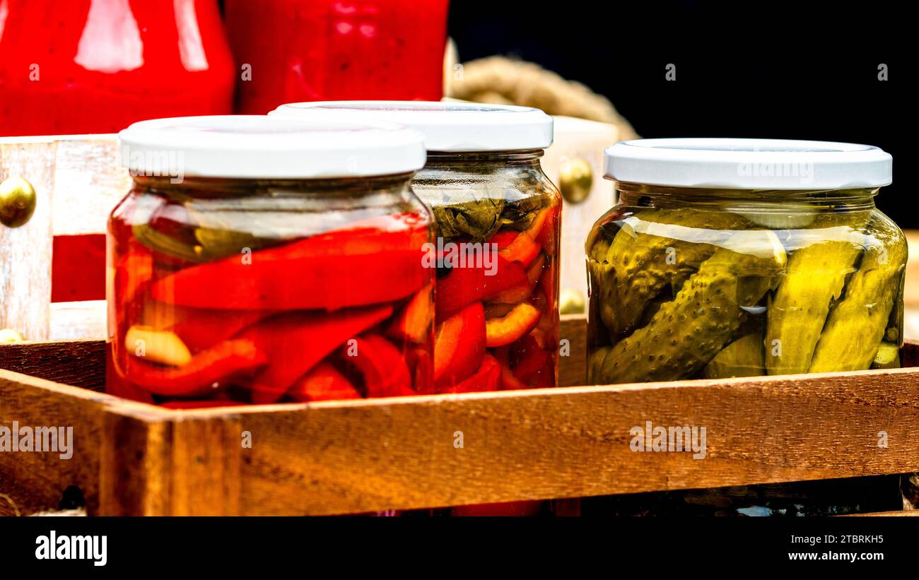 Wooden crate with glass jars with pickled red bell peppers and pickled ...