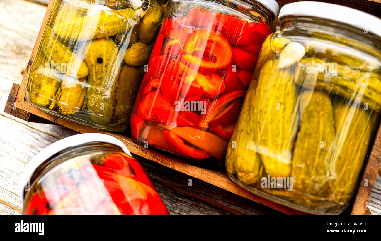 Glass jars with pickled red bell peppers and pickled cucumbers (pickles ...