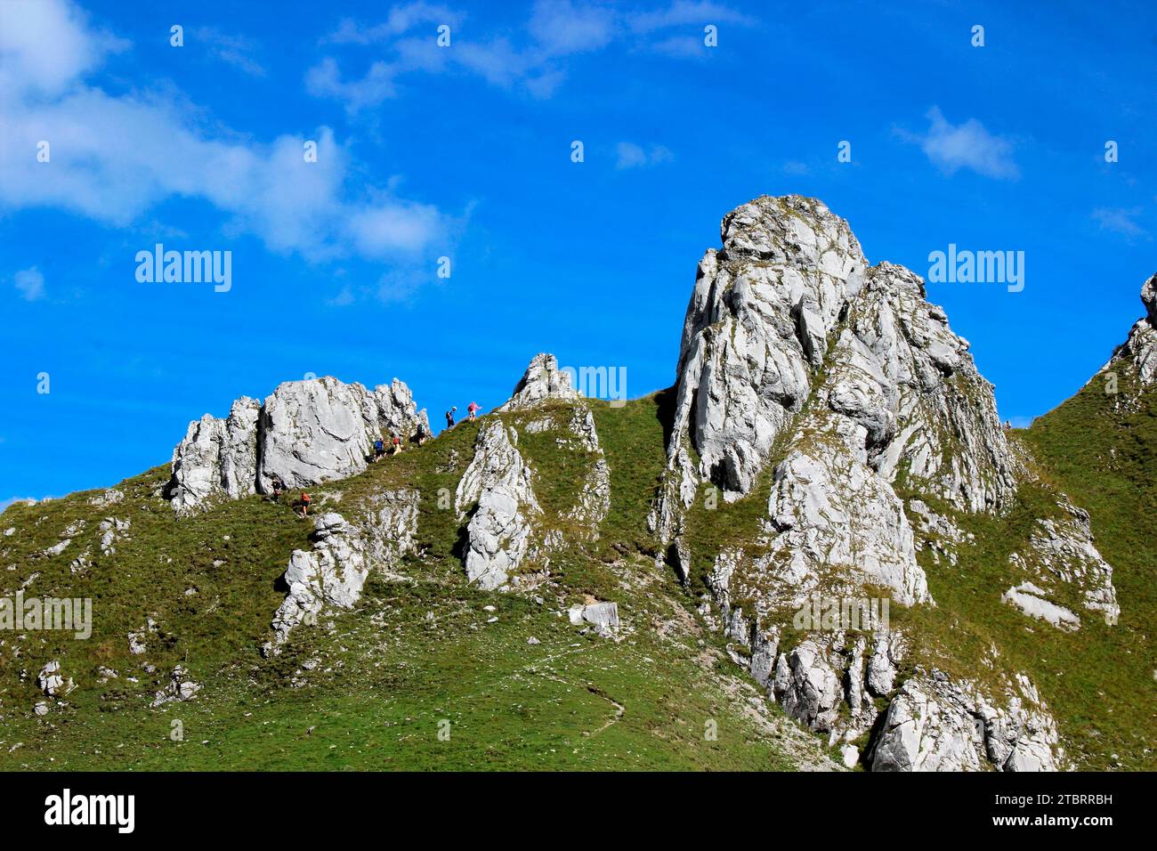 Hikers on the ascent to Torkopf 2014m, in front of a white-blue sky ...