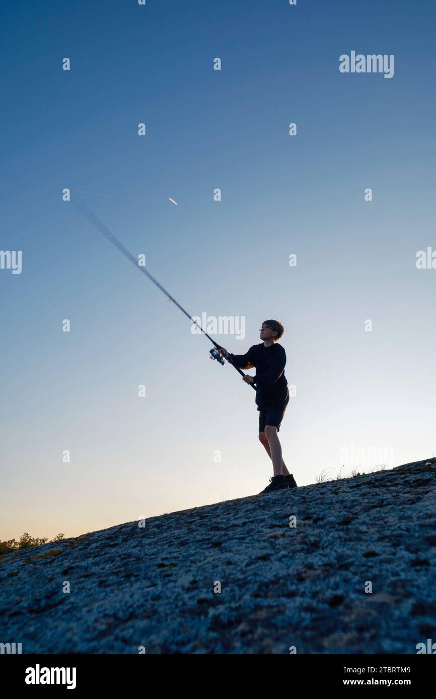 Angler casts his line in the evening twilight Stock Photo - Alamy