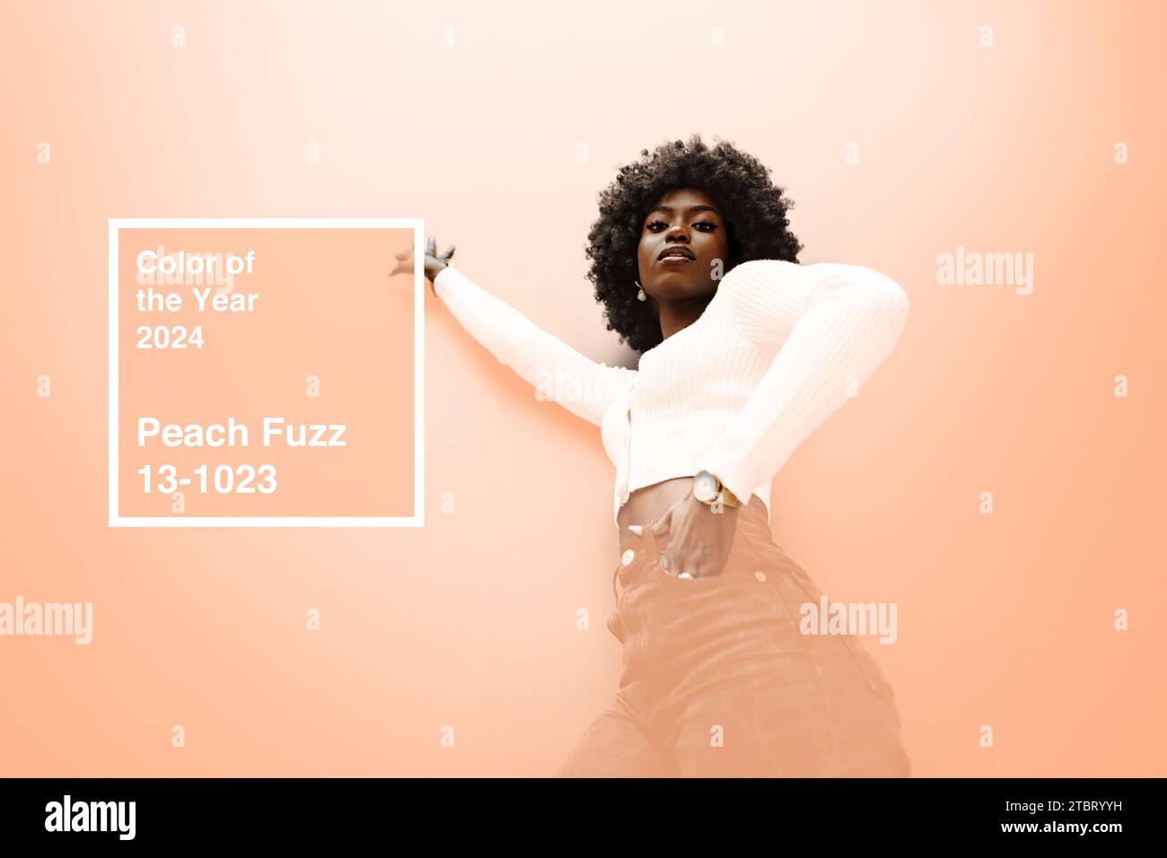 African woman model posing near the wall of Peach fuzz color of the ...