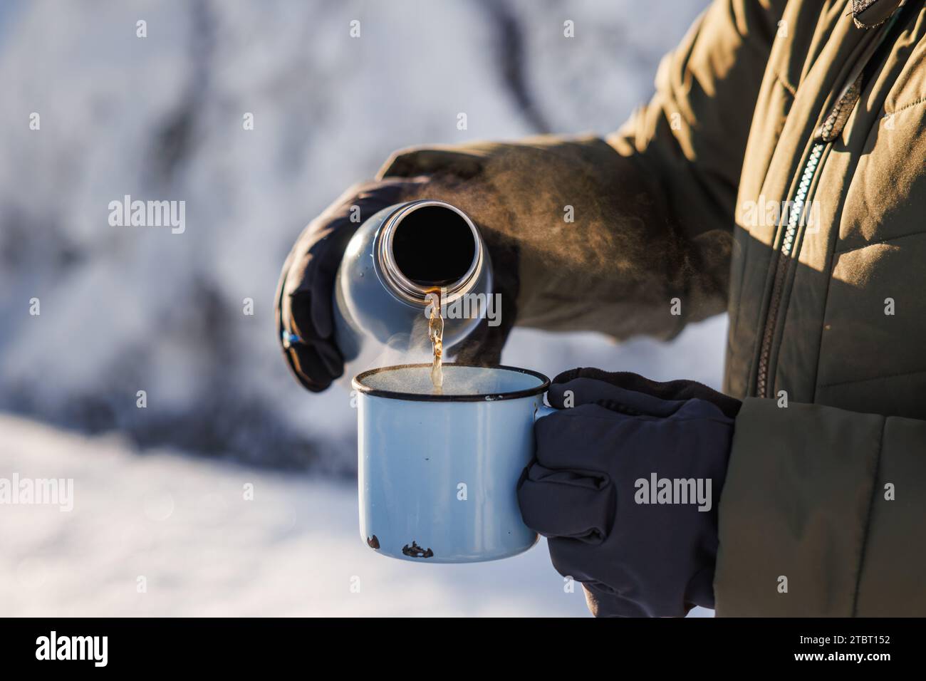 Hiker pouring hot drink from thermos into travel mug. Refreshment ...