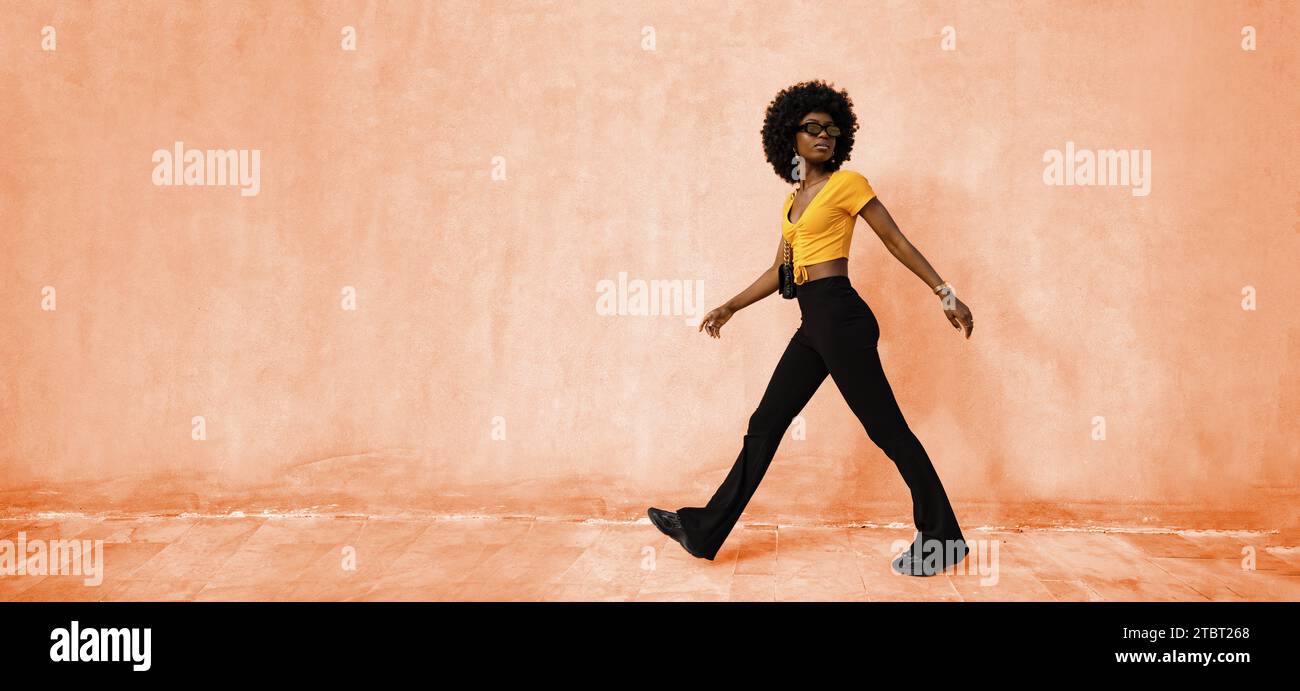 African woman model posing near the wall of Peach fuzz color of the ...