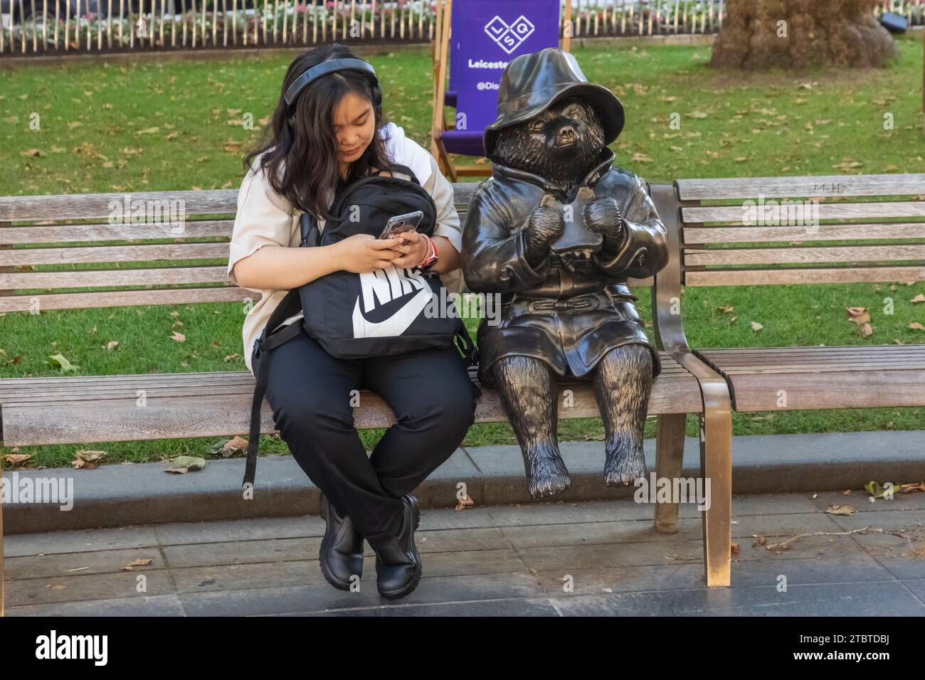 England, London, Leicester Square, Female Asian Tourist Sitting next to ...