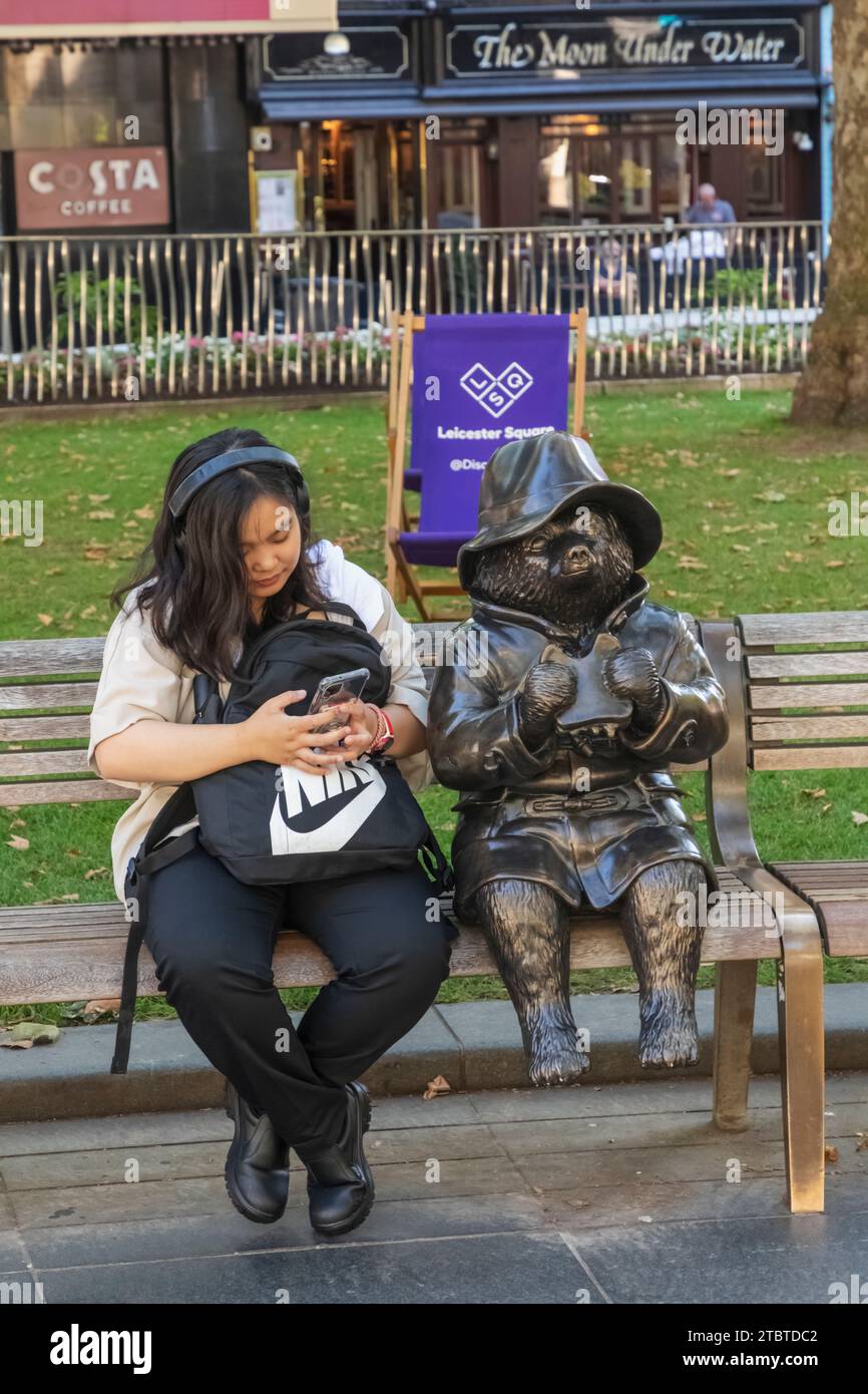 Female asian tourist sitting next to statue of paddington bear hi-res ...