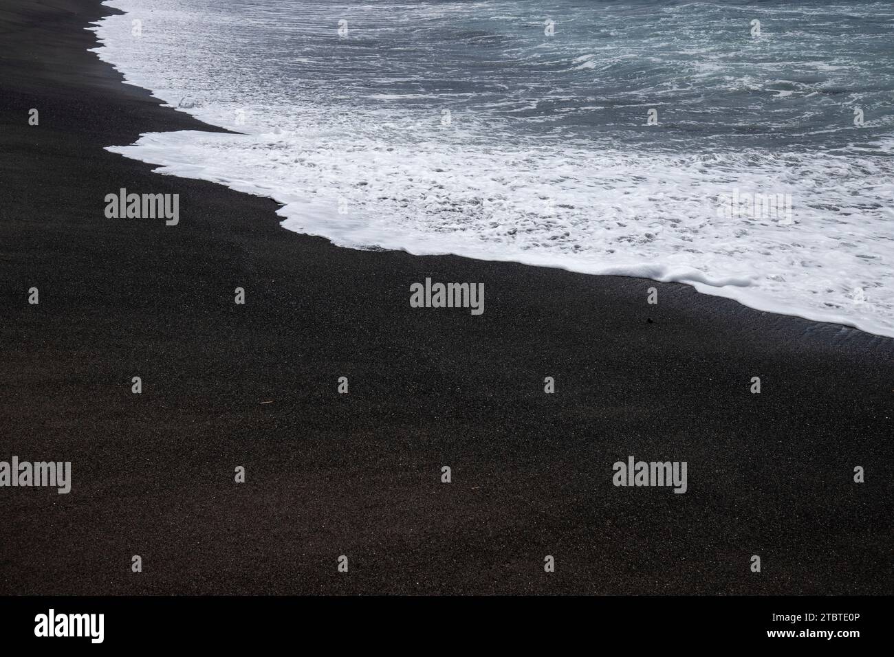 A black sand beach directly by the sea, beautiful beach with waves ...