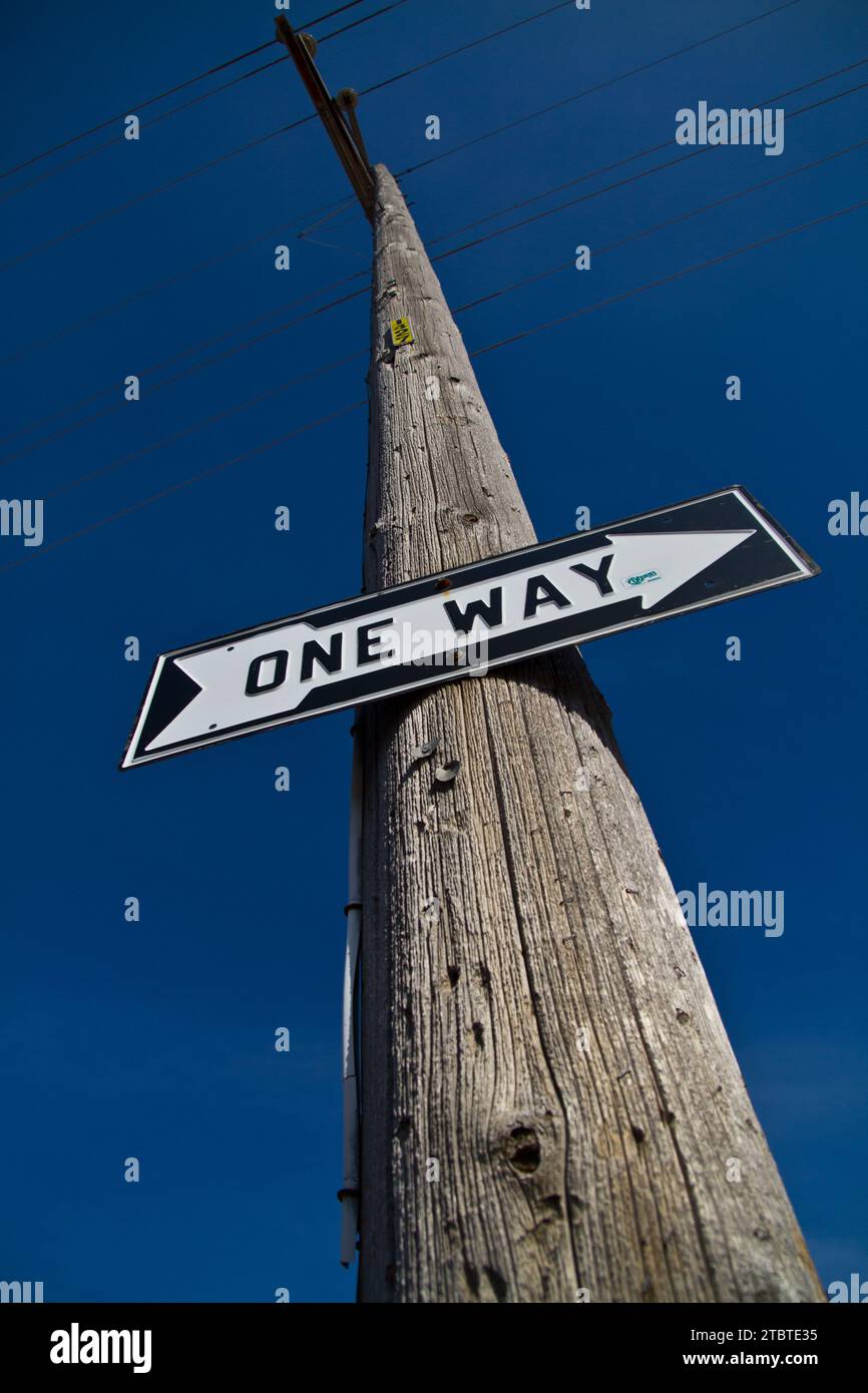 One Way Sign on Weathered Utility Pole Against Clear Blue Sky Stock ...