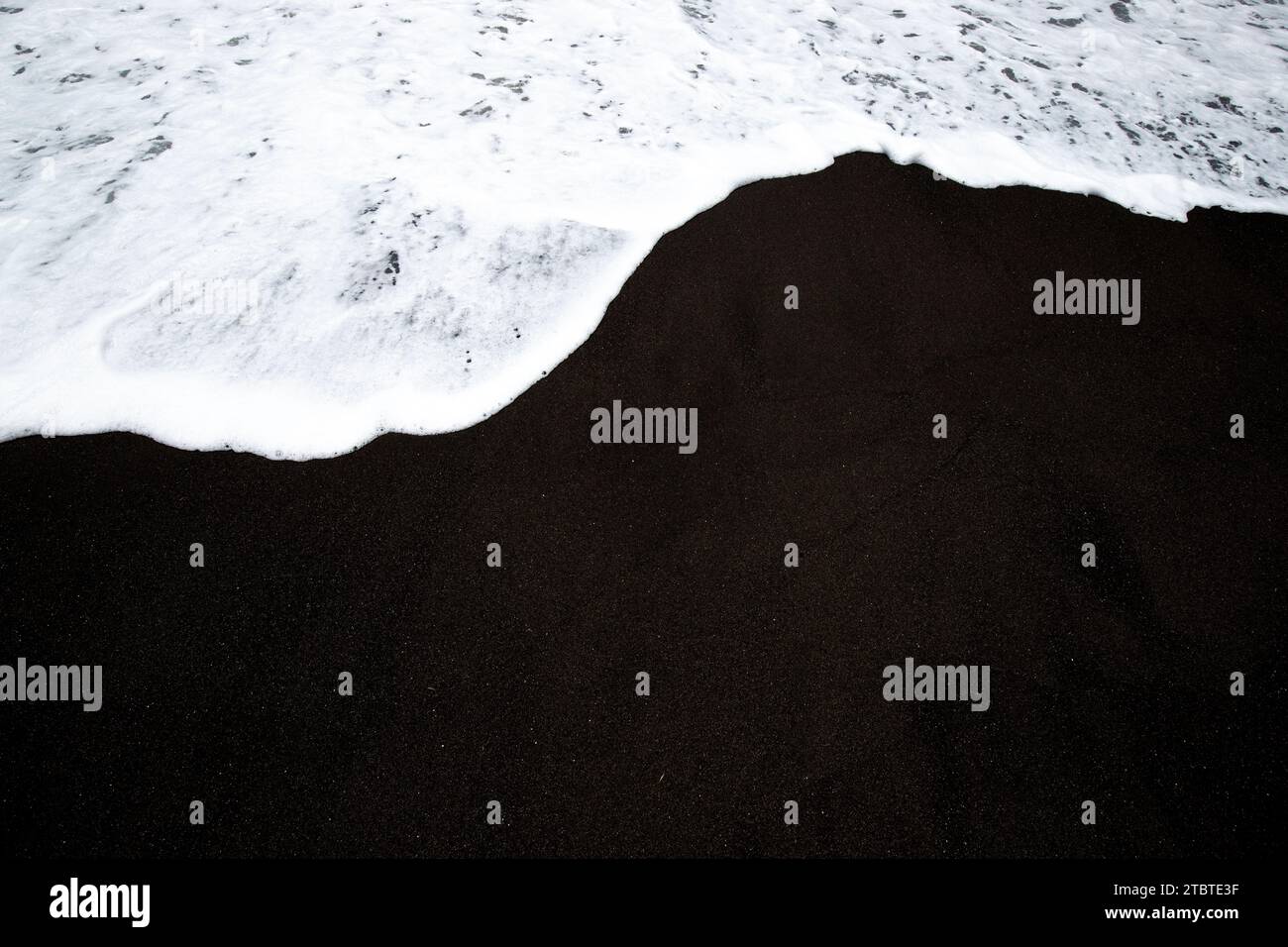 A black sand beach directly by the sea, beautiful beach with waves ...