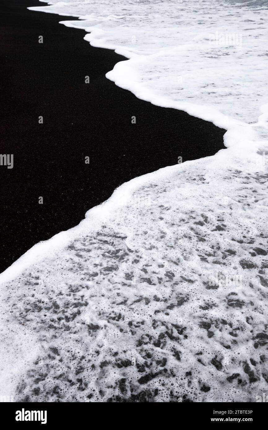 A black sand beach directly by the sea, beautiful beach with waves ...