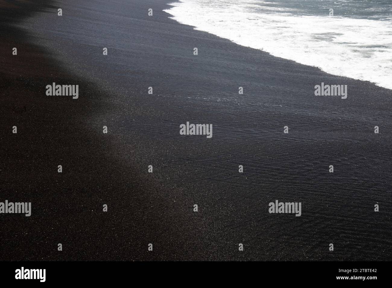 A black sand beach directly by the sea, beautiful beach with waves ...