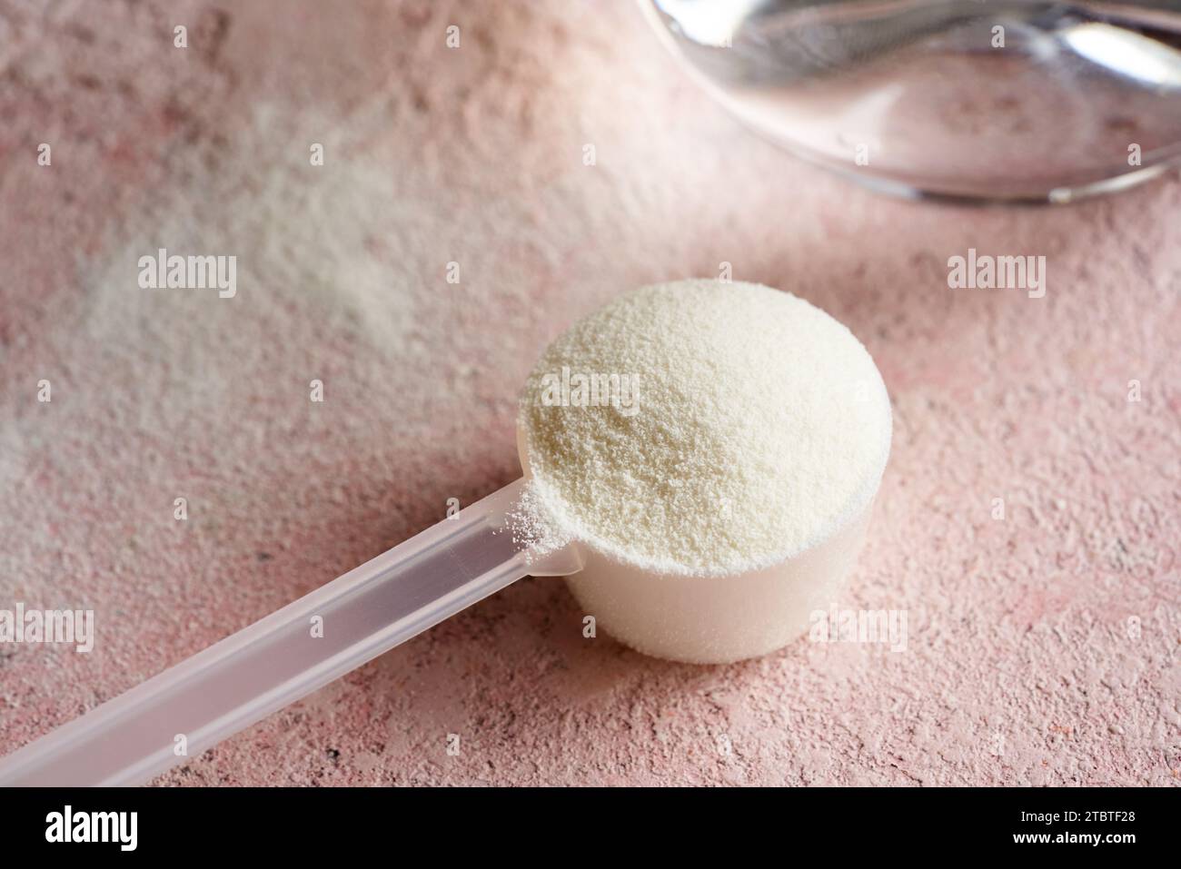 Collagen powder in a plastic measuring scoop on pink background Stock ...