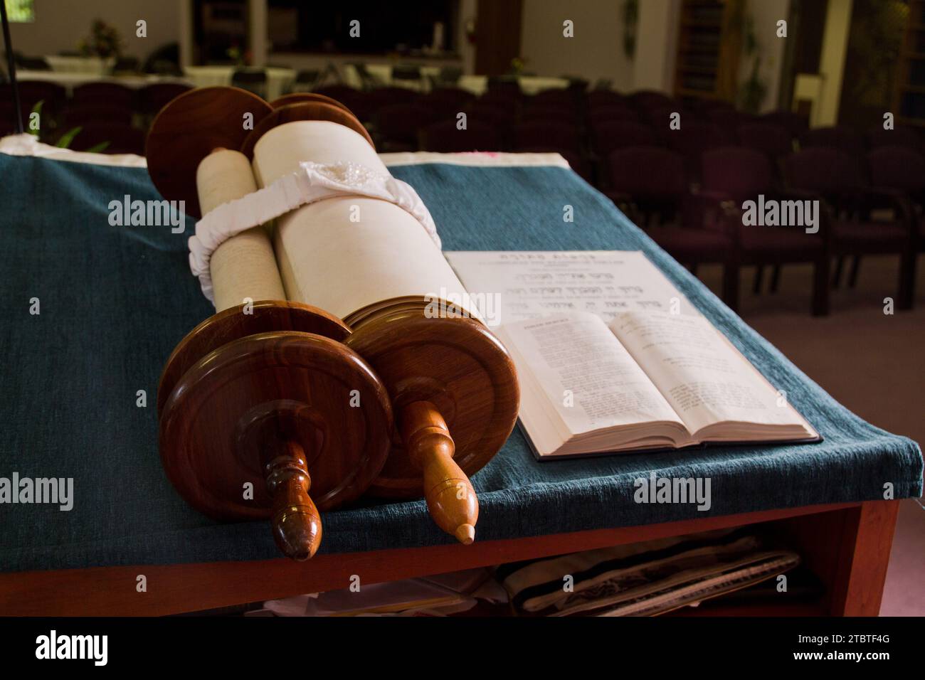 Torah Scroll on Blue Cloth with Empty Synagogue Chairs in Background ...