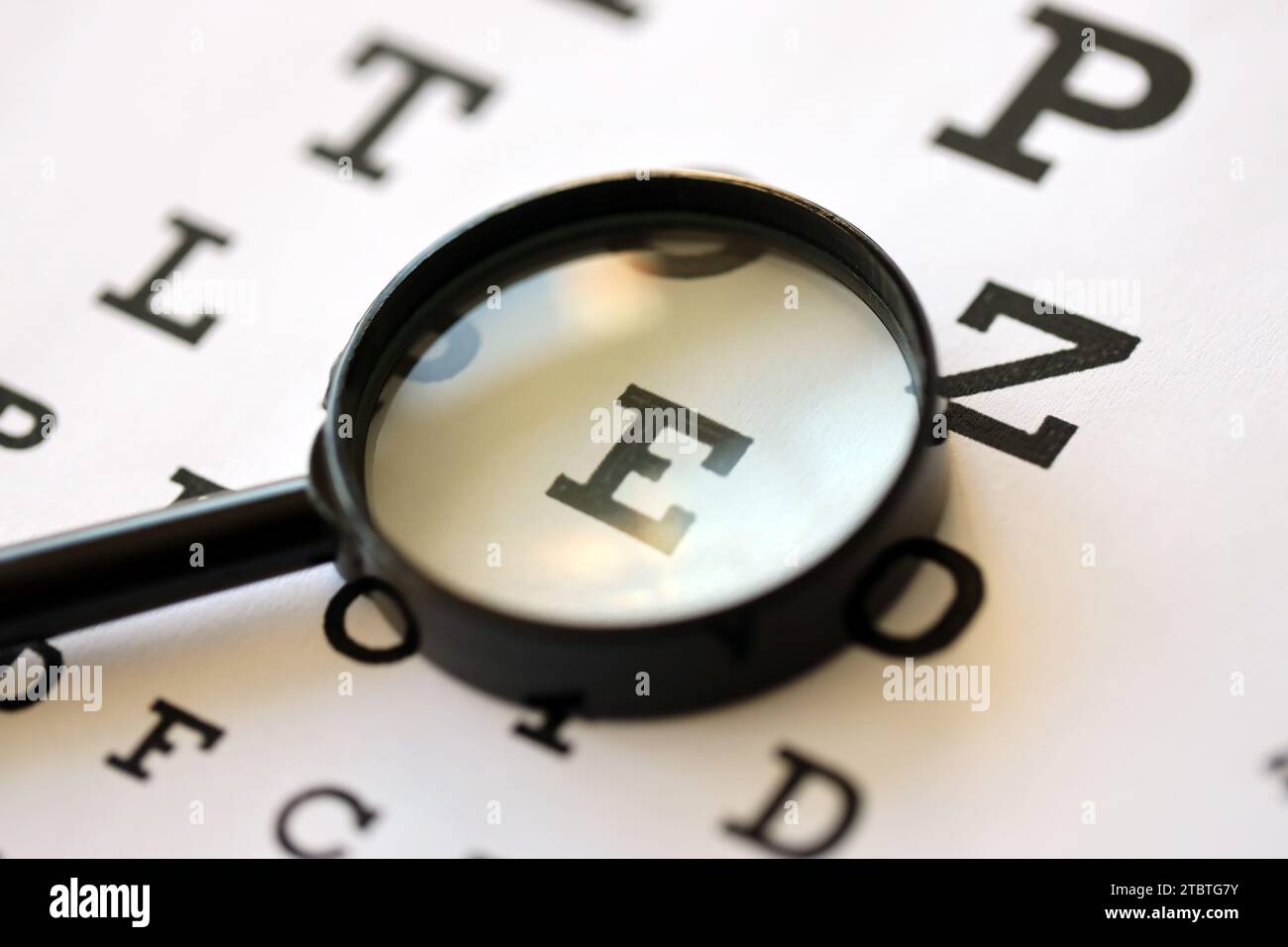 Magnifier glass focuses eye chart letters clearly and lies on eye test ...
