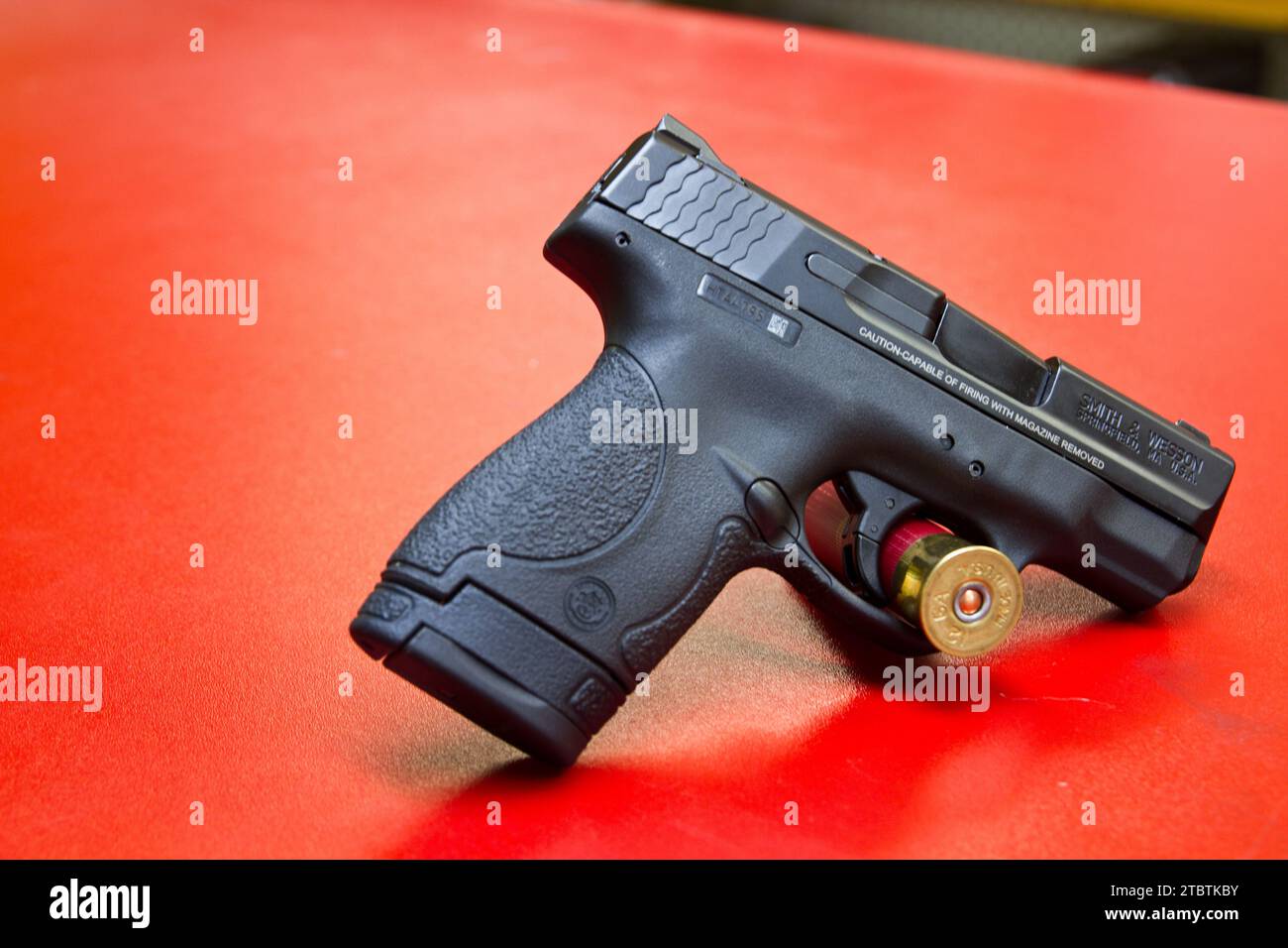 Black Semi-Automatic Pistol with Laser Sight and Bullet on Vibrant Red ...