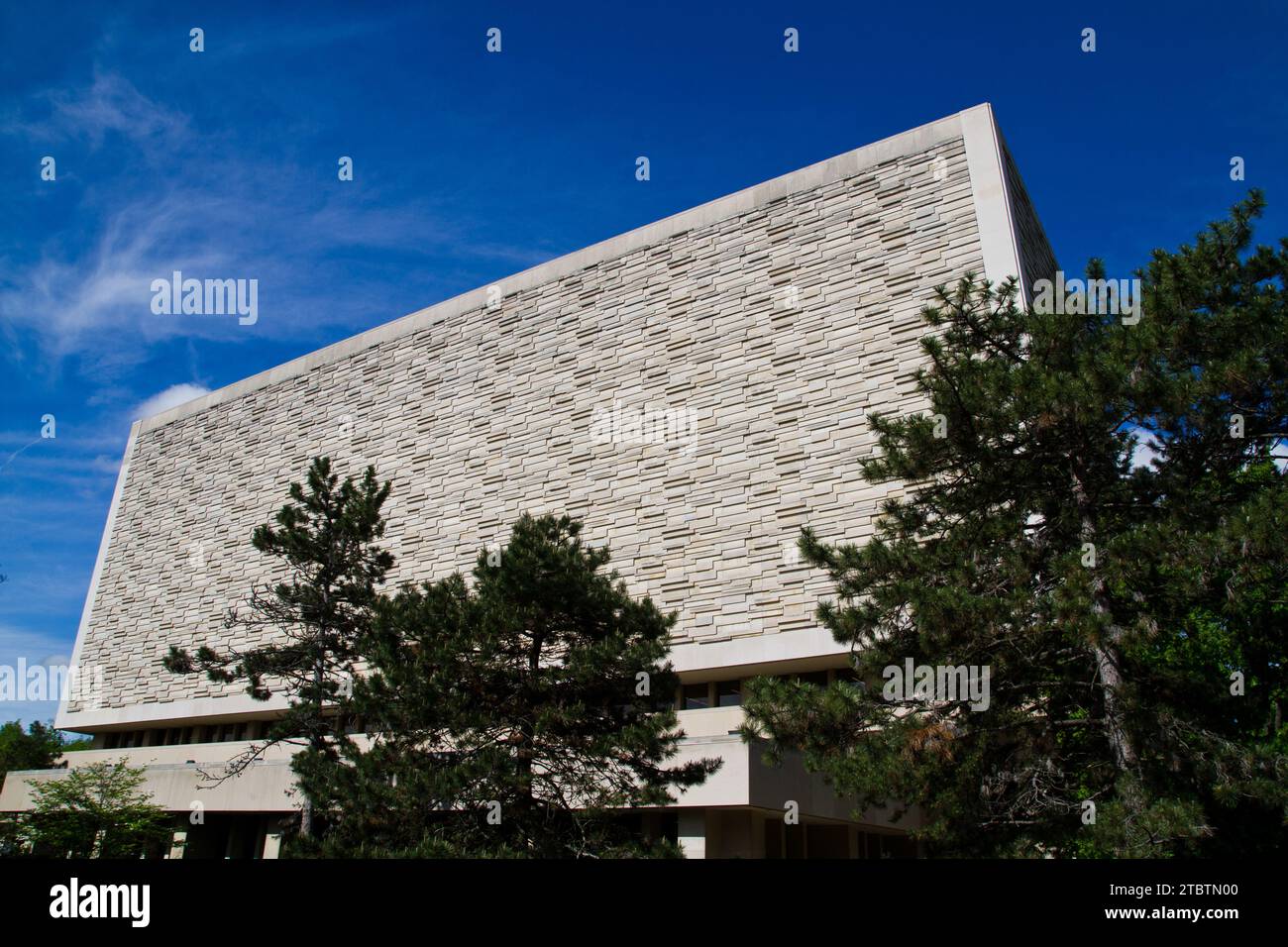Modern Angular Building with Textured Facade Framed by Green Trees in ...