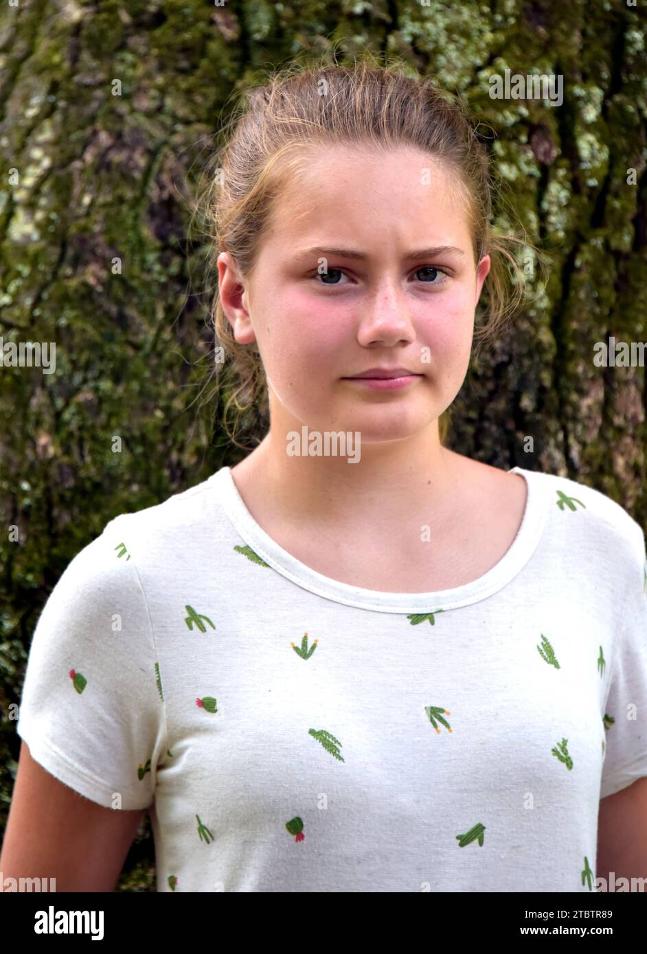 Young teen leans against a tree with a puzzled, frowning look on her ...