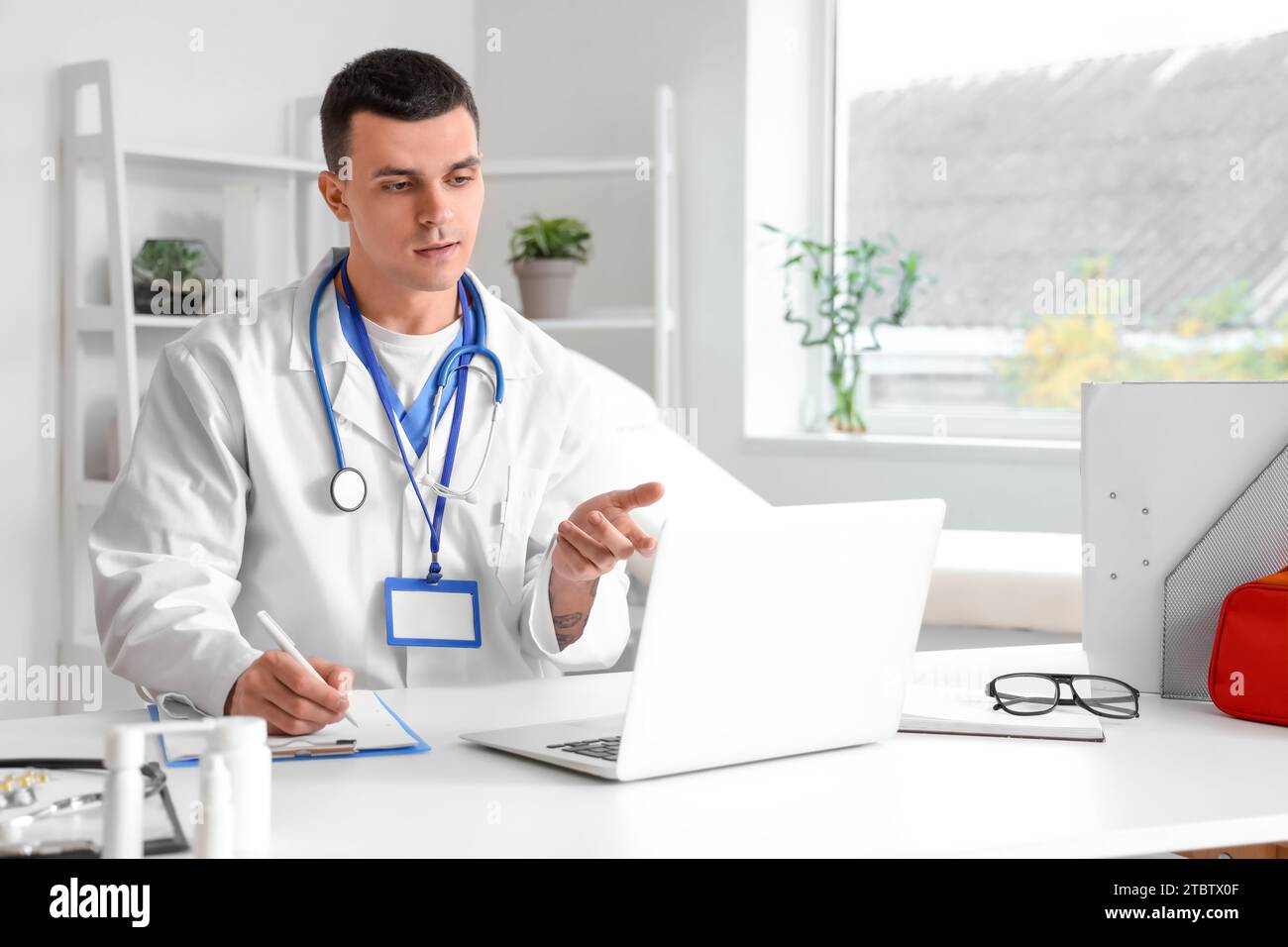 Male doctor video chatting with patient on laptop in office Stock Photo ...