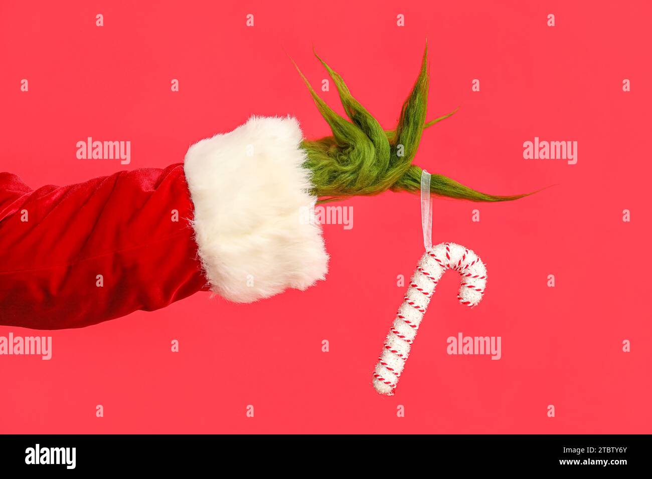 Green hairy hand of creature in Santa costume with decorative candy ...