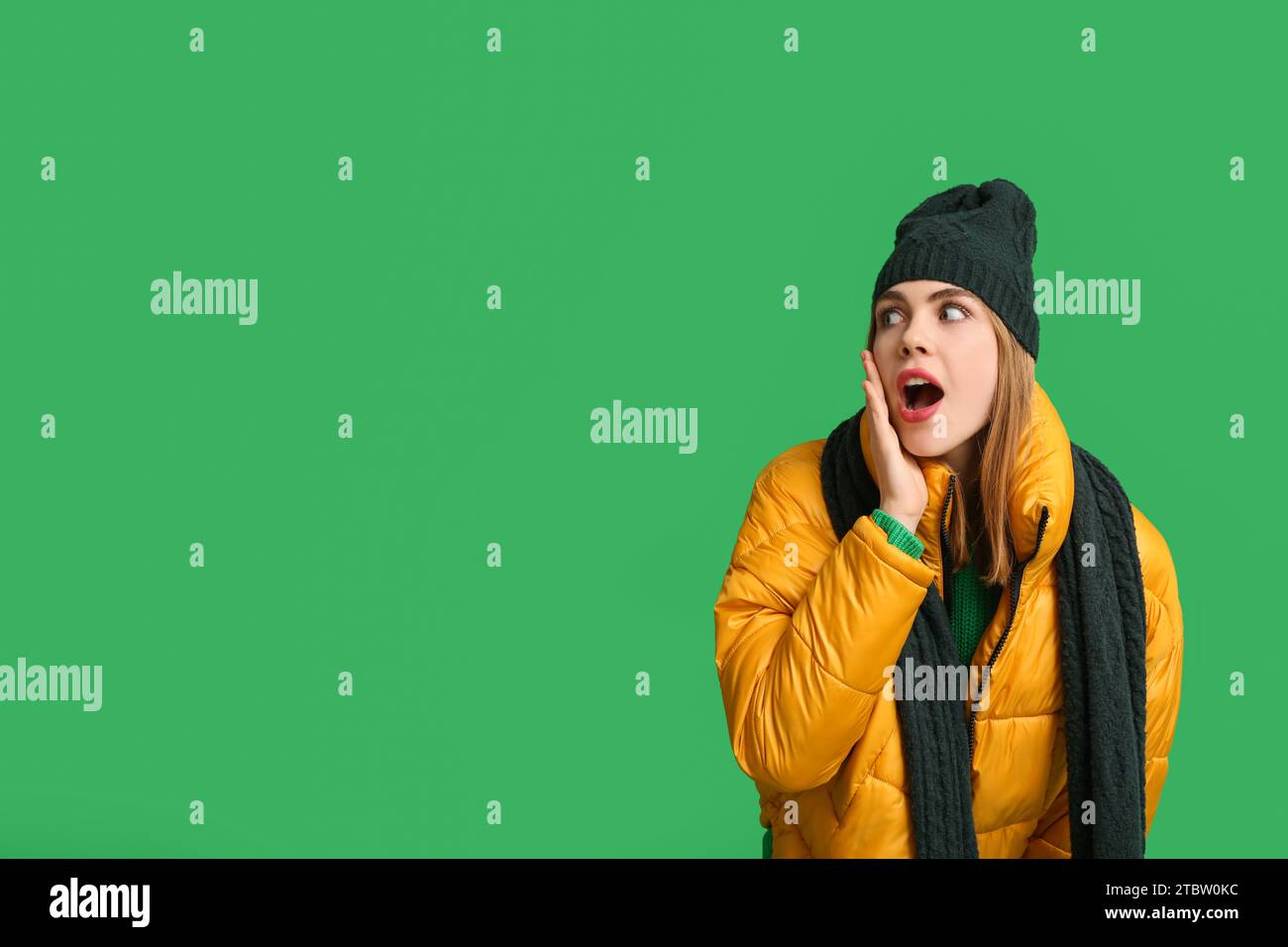 Beautiful young shocked woman in warm winter clothes on green ...