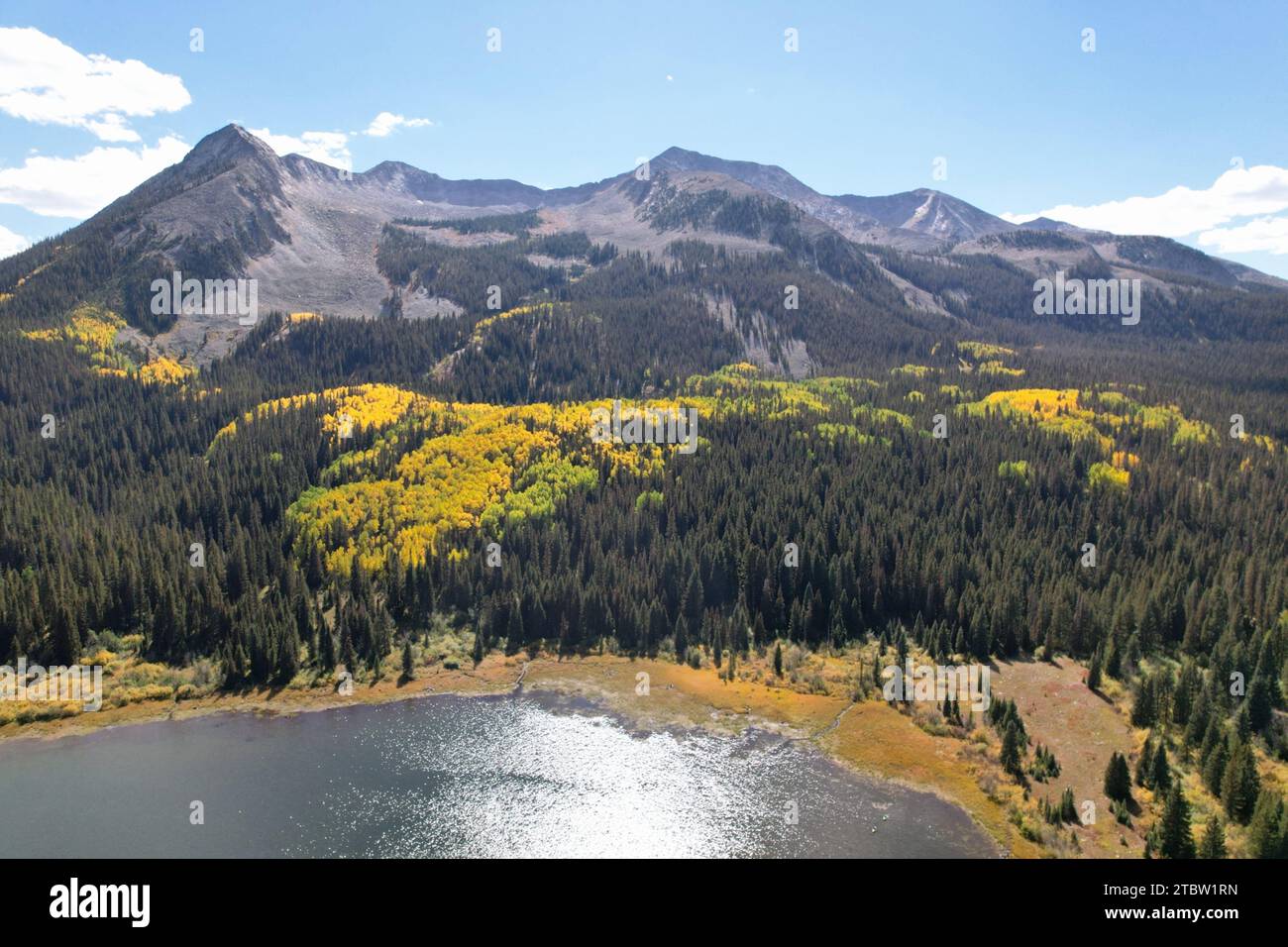 A serene lake surrounded by lush green trees and dramatic mountain ...
