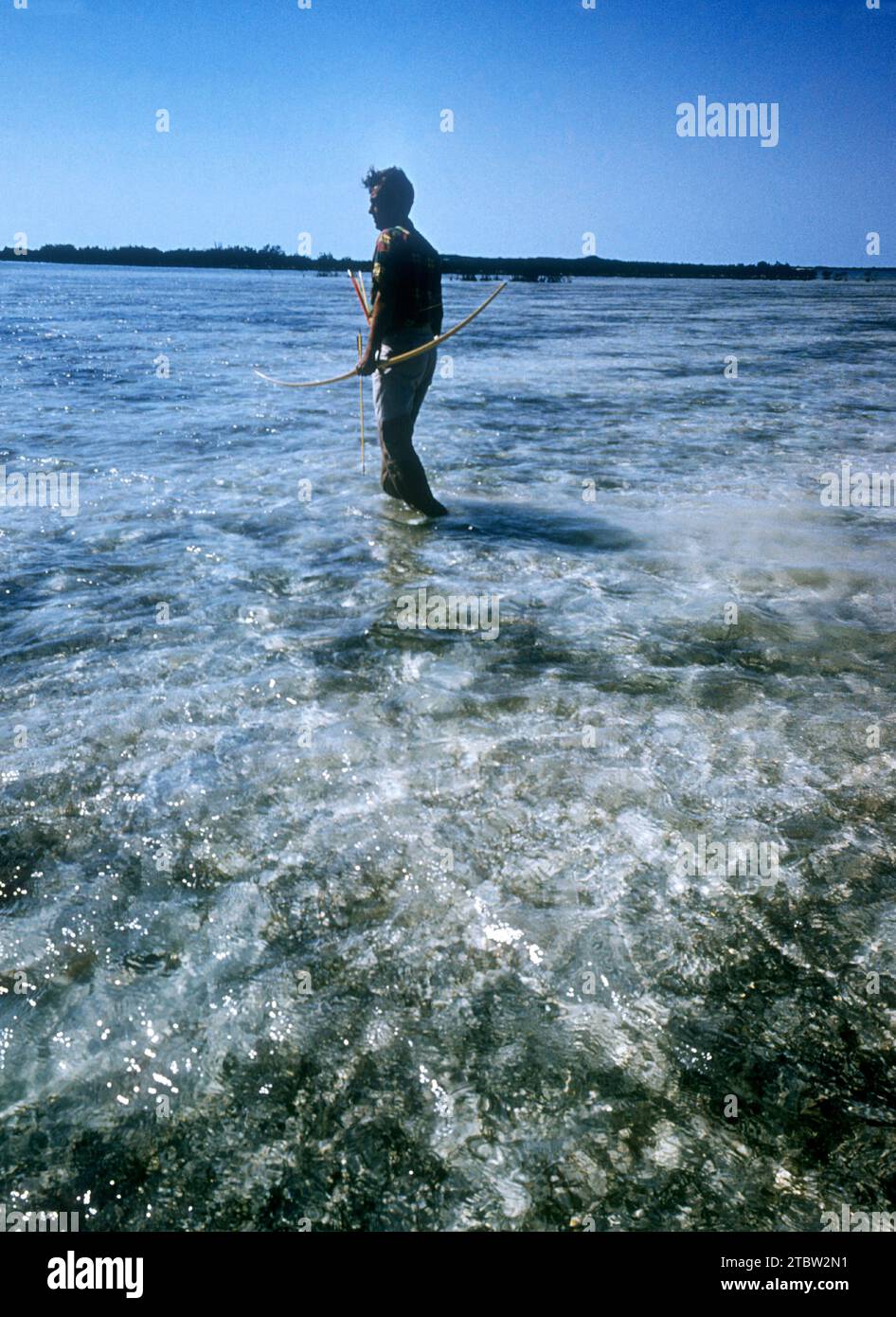 BAHAMAS - APRIL 7: Colyn Rees walks in the water with his bow and arrow ...