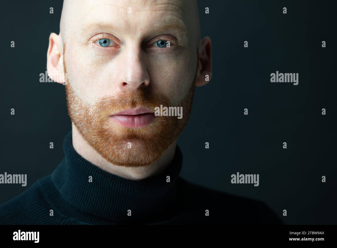 A man with a red beard looking straight and confident in black clothes ...