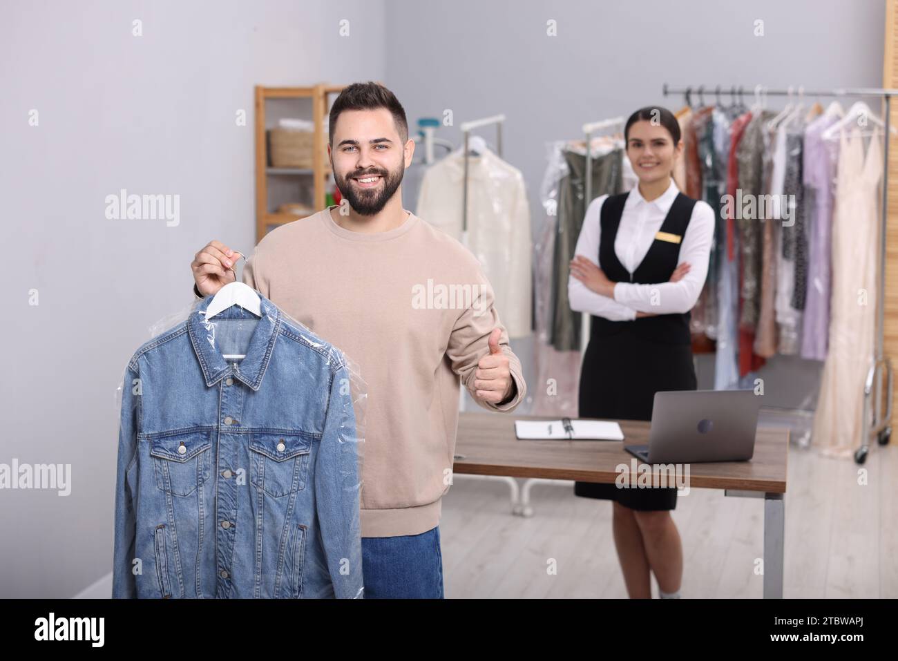 Dry-cleaning service. Man holding hanger with denim jacket and showing ...