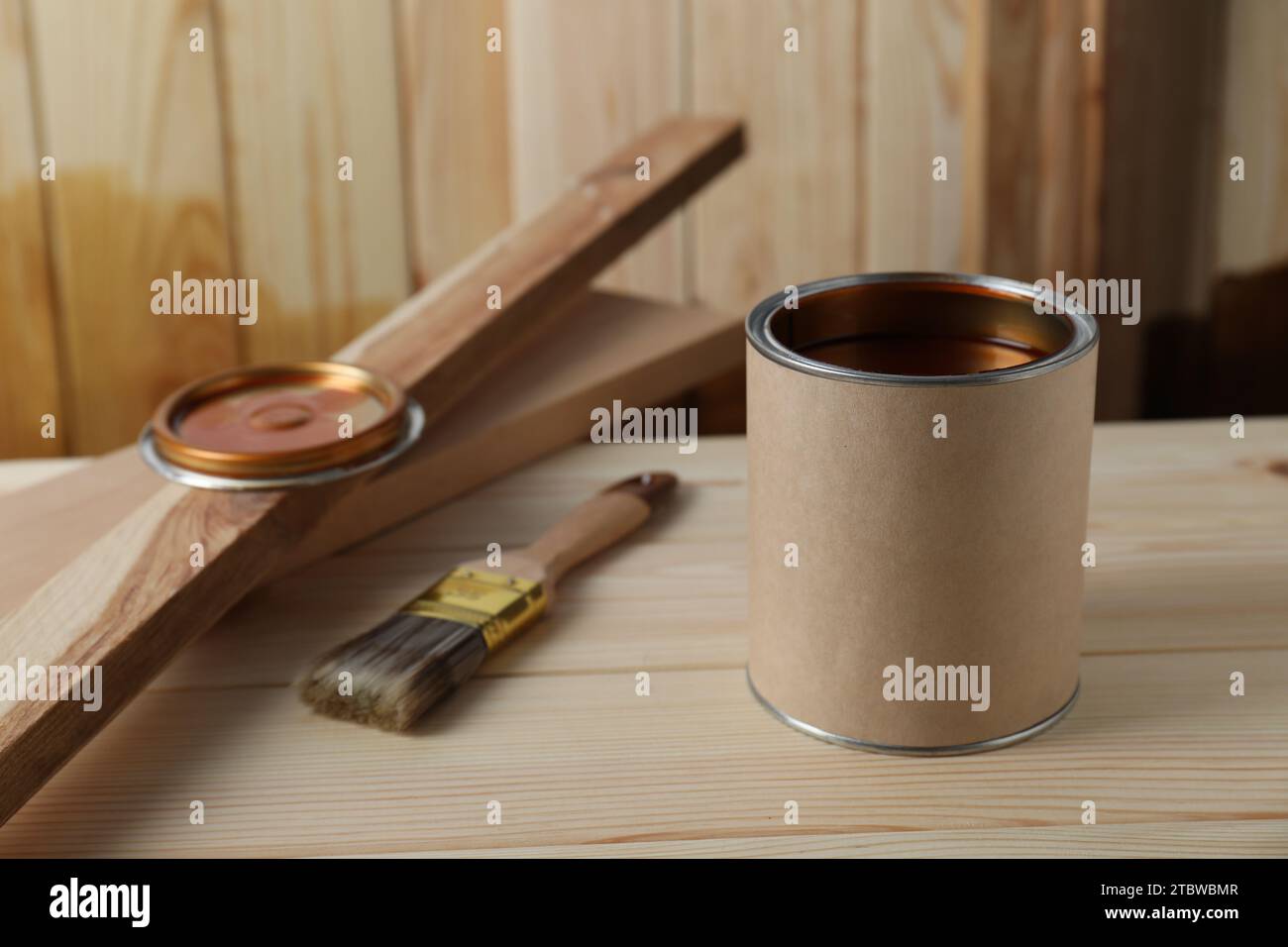 Can and brush with wood stain on wooden surface Stock Photo - Alamy