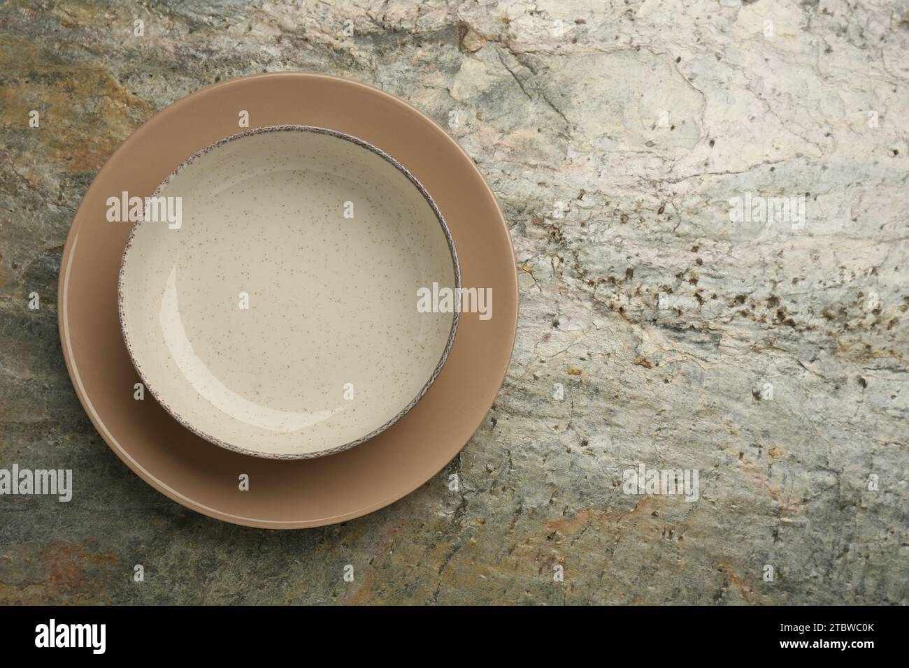 Beautiful beige ceramic plates on gray textured table, top view. Space ...
