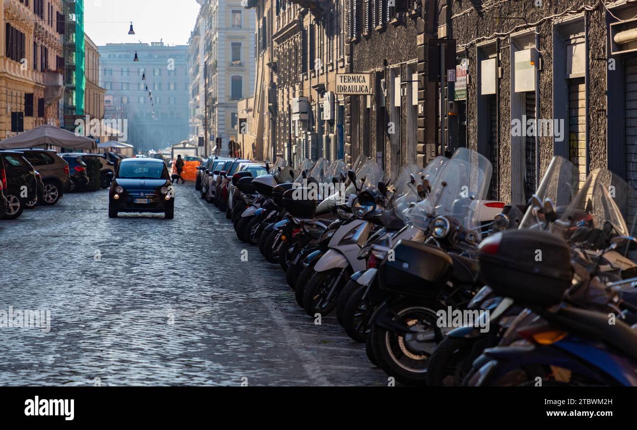A picture of a street in Rome with a long line of scooters on the right ...