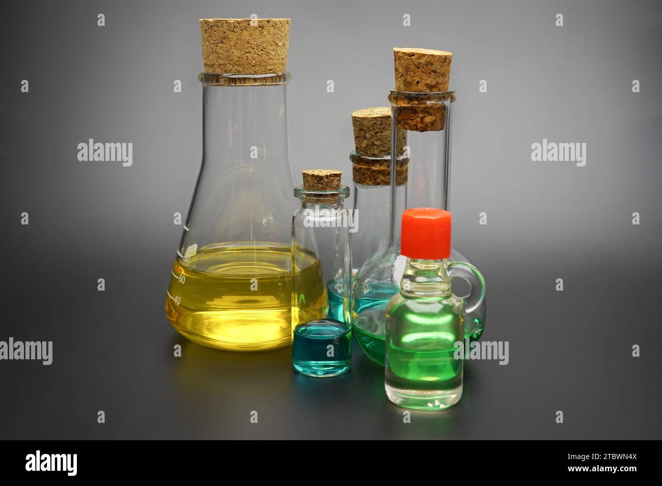 Assorted colourful solutions or essential oils in glass containers with ...