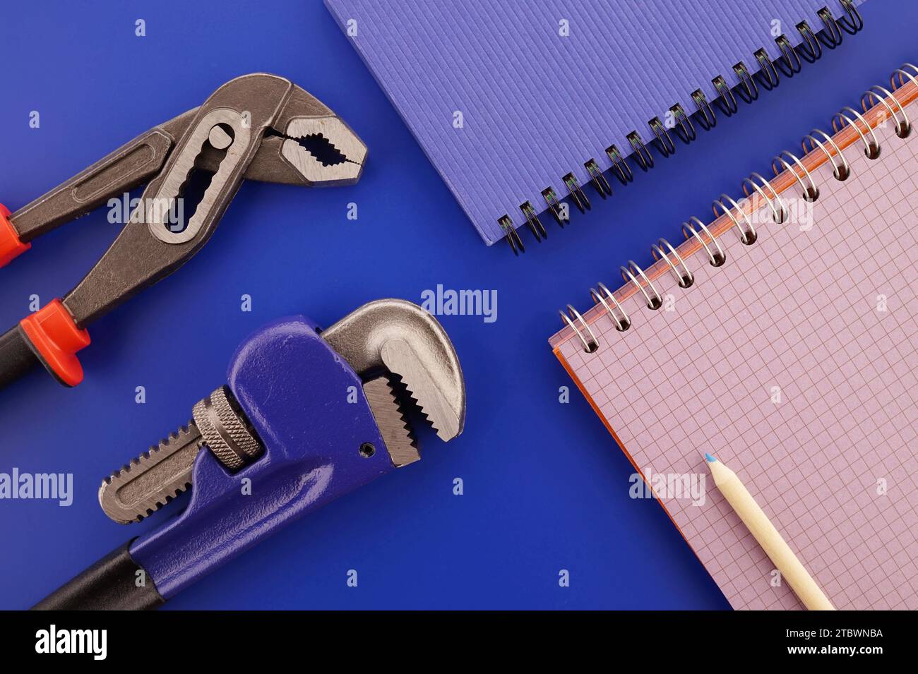 Plumbing equipment and wire bound open notebooks on blue background ...