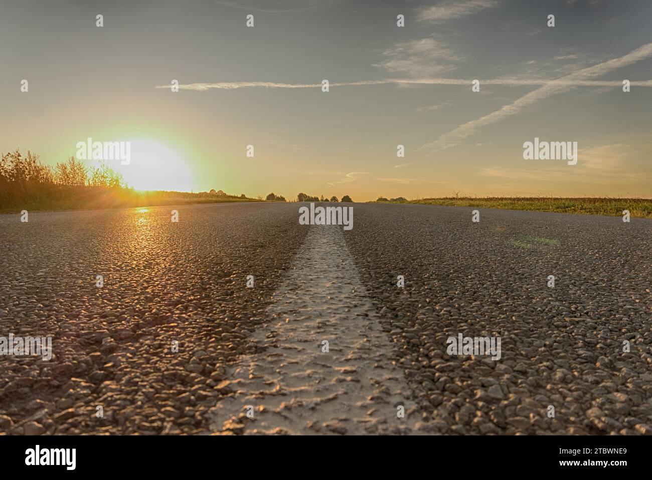 Ground level view of an asphalt road in the countryside at sunset with ...