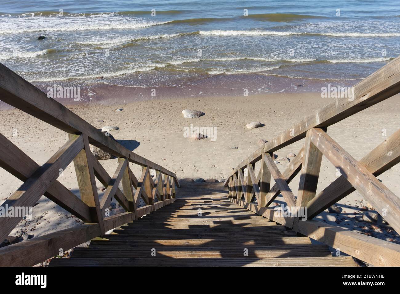 Flight of wooden steps leading down to a sandy beach with gentle surf ...