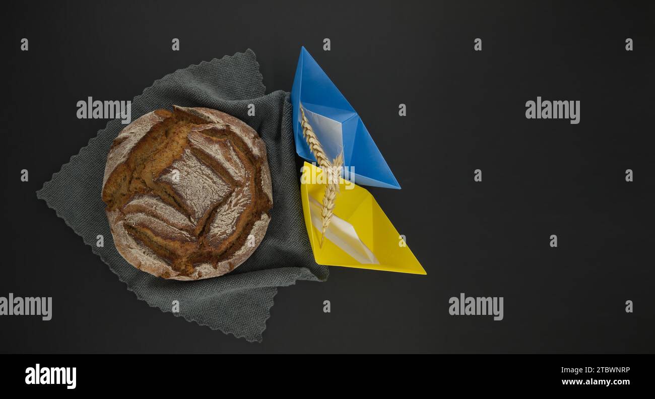 Bread loaf placed on a black table near Ukrainian flag colors origami ...