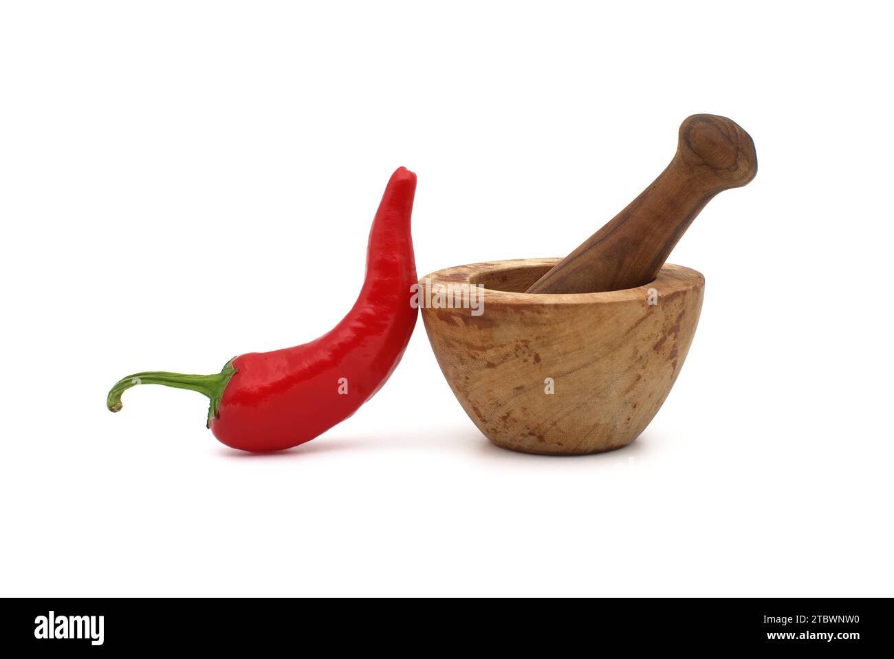 Old rustic wooden pestle and mortar alongside an fresh red chili pepper ...