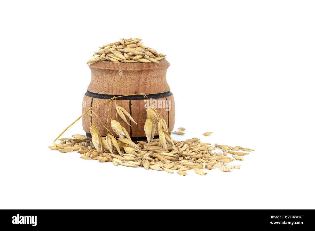 Heap of organic oat grains with hulls or husks in small wooden barrel ...
