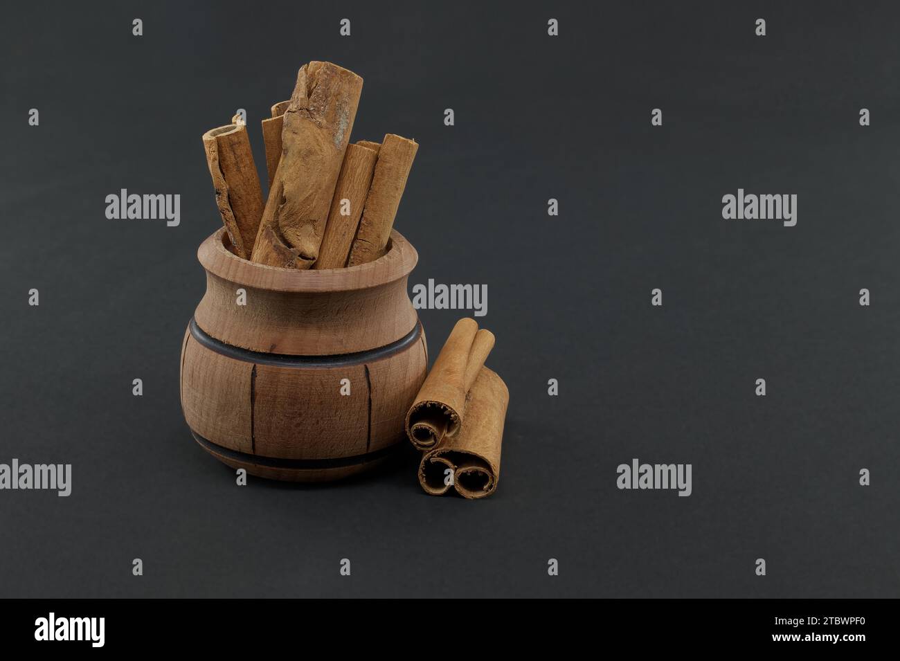 Cinnamon sticks bundle in a small wooden pot over black background with ...