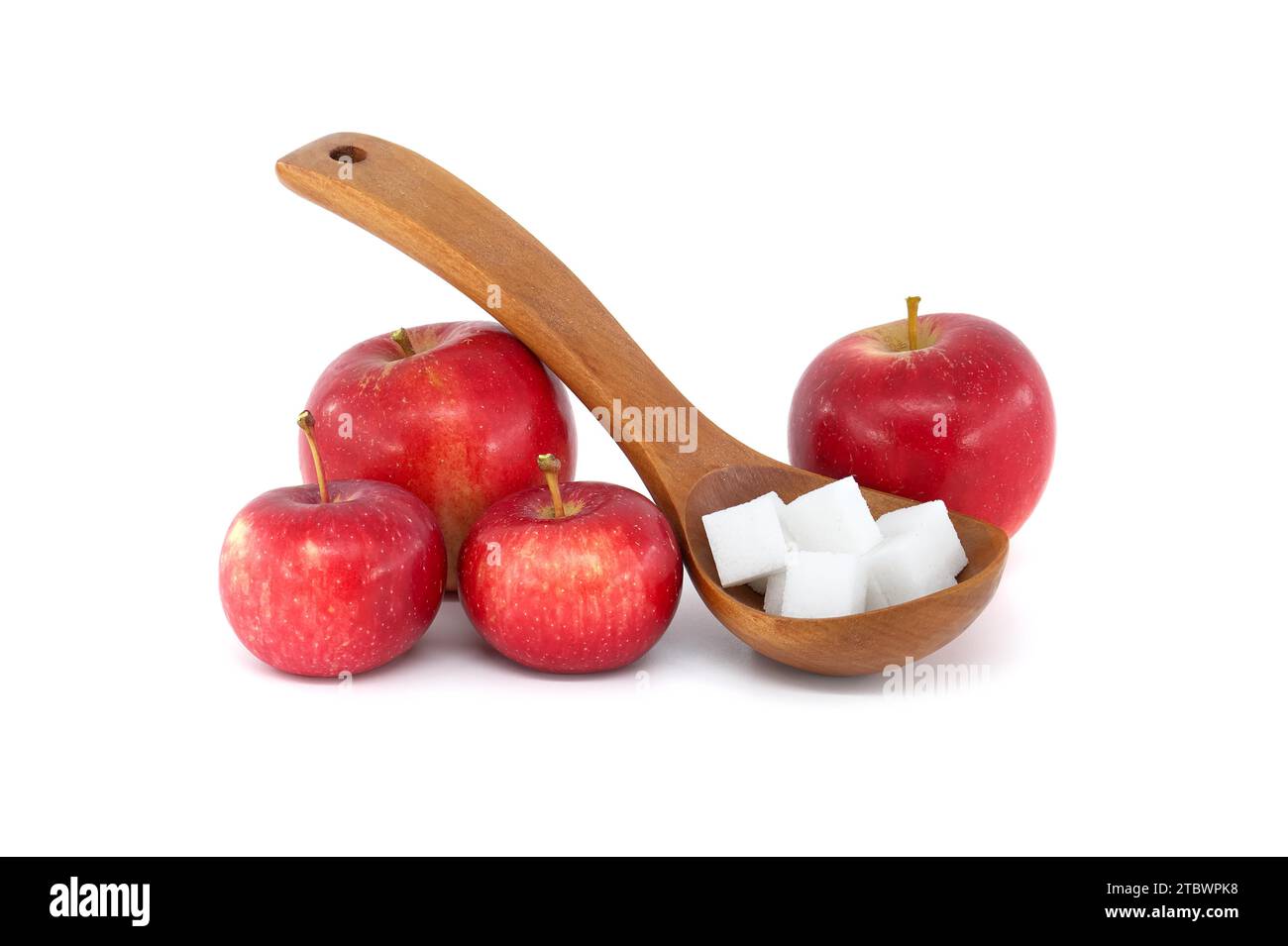 Red apples of different sizes and sugar placed in a carved wooden spoon ...