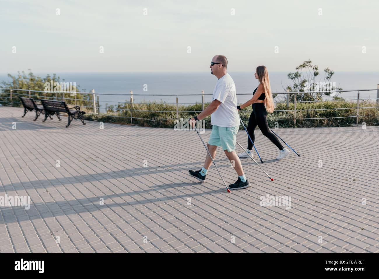 Happy Middle aged couple or friends practicing nordic walking in park ...