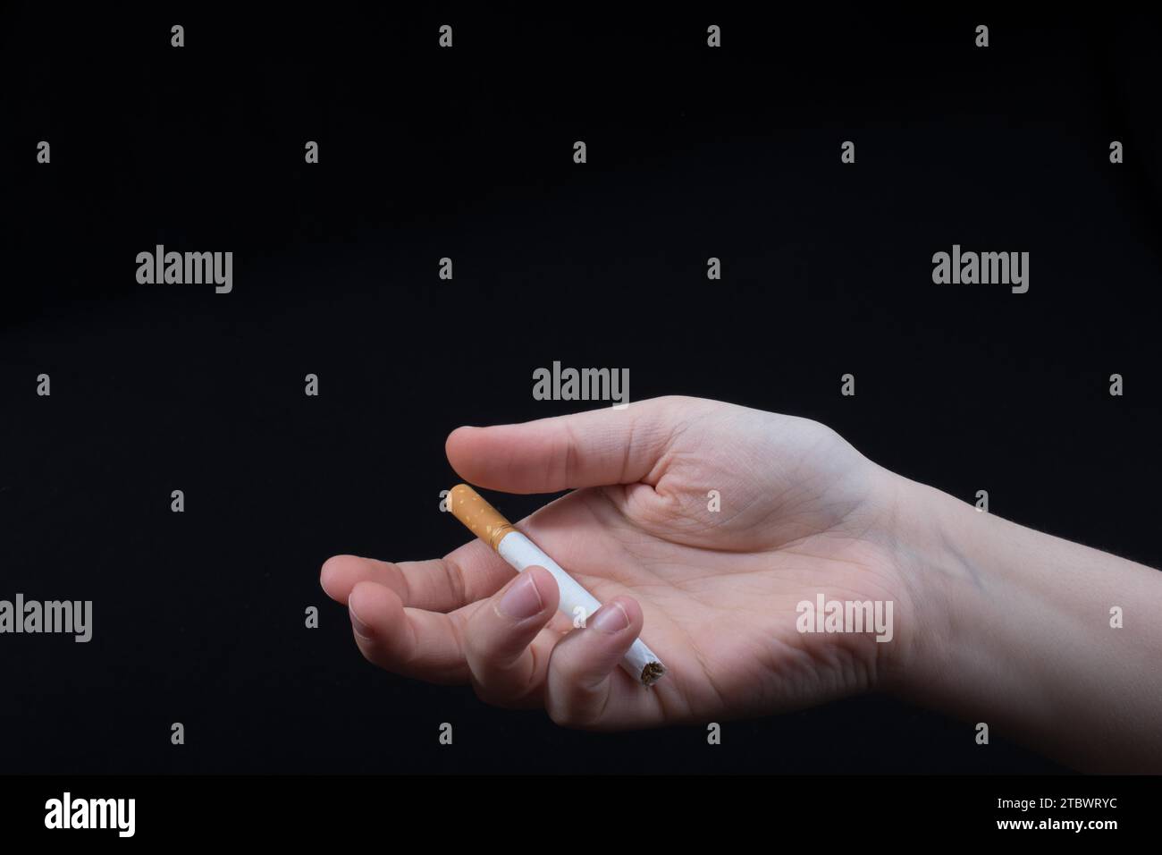 Hand is giving out cigarette on a black background Stock Photo - Alamy