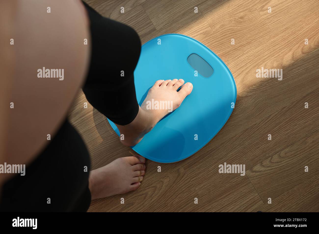 Lower body of a woman standing on a weight scale Stock Photo - Alamy